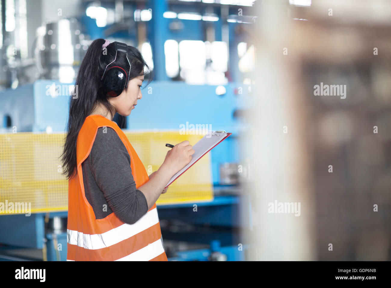 Technician writing on clipboard in factory Stock Photo - Alamy
