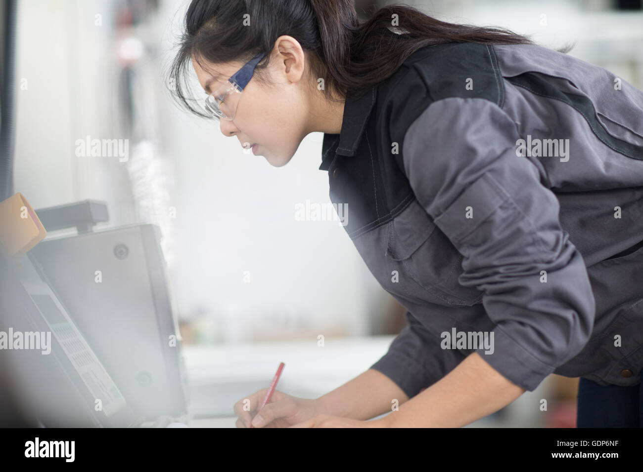 Technician writing notes in factory Stock Photo - Alamy