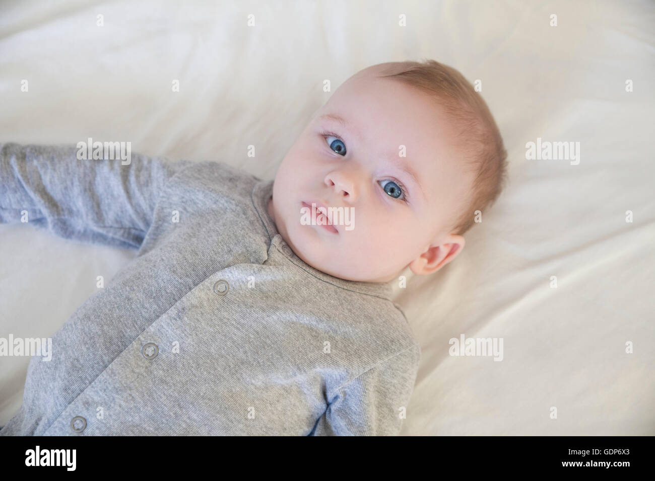Overhead portrait of blue eyed baby boy lying on bed Stock Photo - Alamy