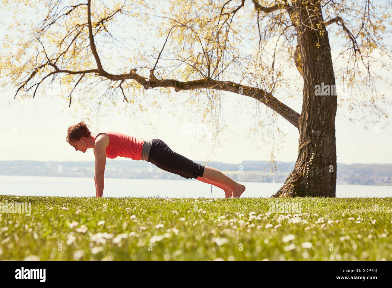 Side view of woman doing yoga push up Stock Photo - Alamy