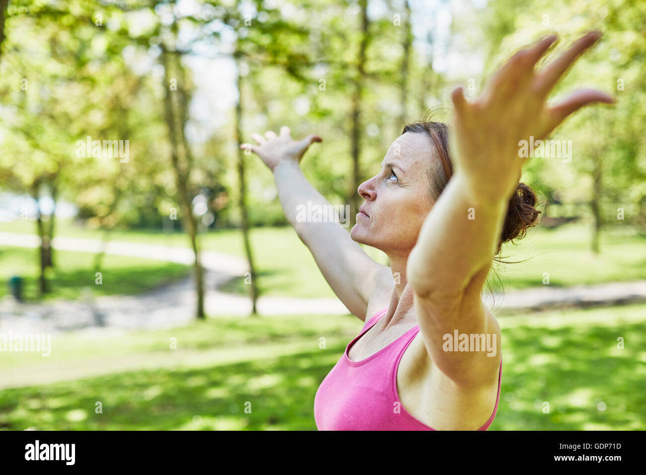 Side view of woman looking up arms raised stretching Stock Photo - Alamy