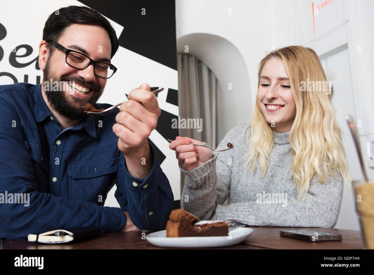 Happy couple eating chocolate brownies at cafe table Stock Photo - Alamy