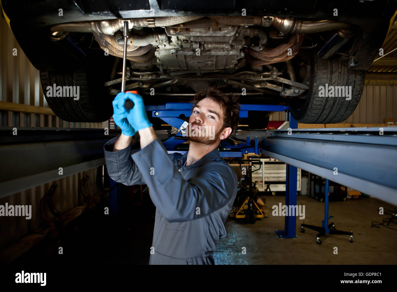 Male mechanic doing maintenance under car Stock Photo - Alamy