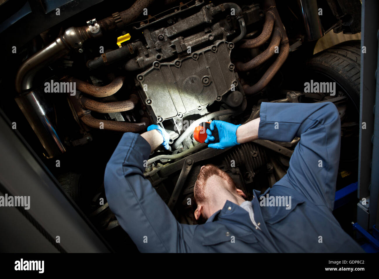 Male mechanic holding torch, looking under car Stock Photo - Alamy