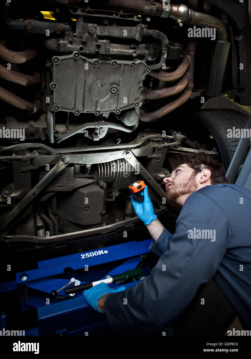 Male mechanic holding torch, looking under car Stock Photo - Alamy