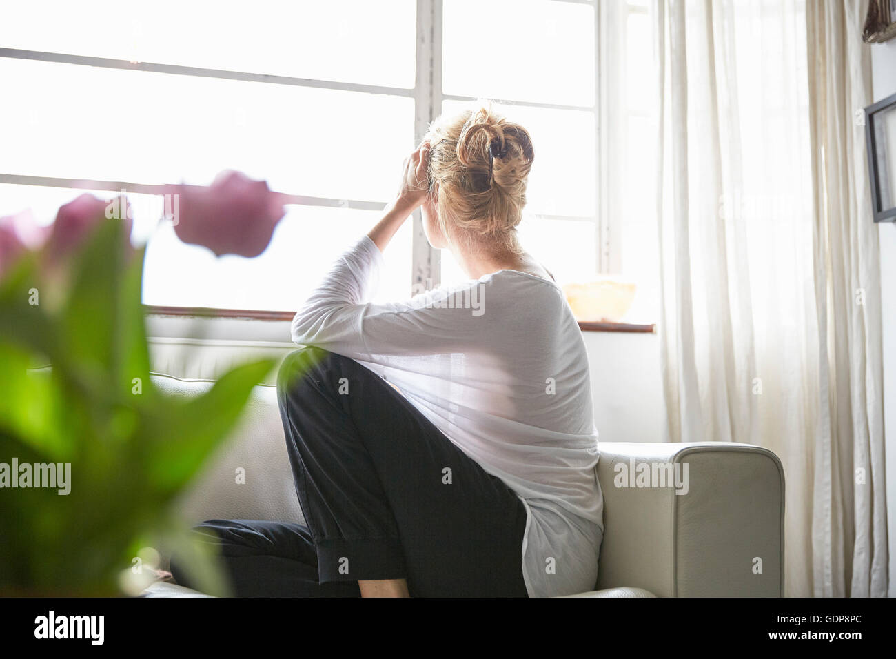 Woman sitting in front of window looking out Stock Photo - Alamy