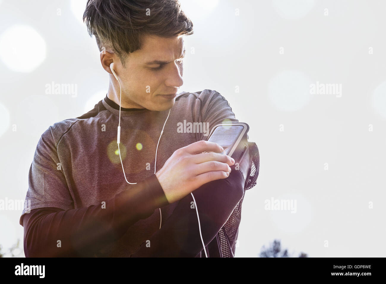 Young man outdoors, adjusting mp3 player on arm Stock Photo - Alamy