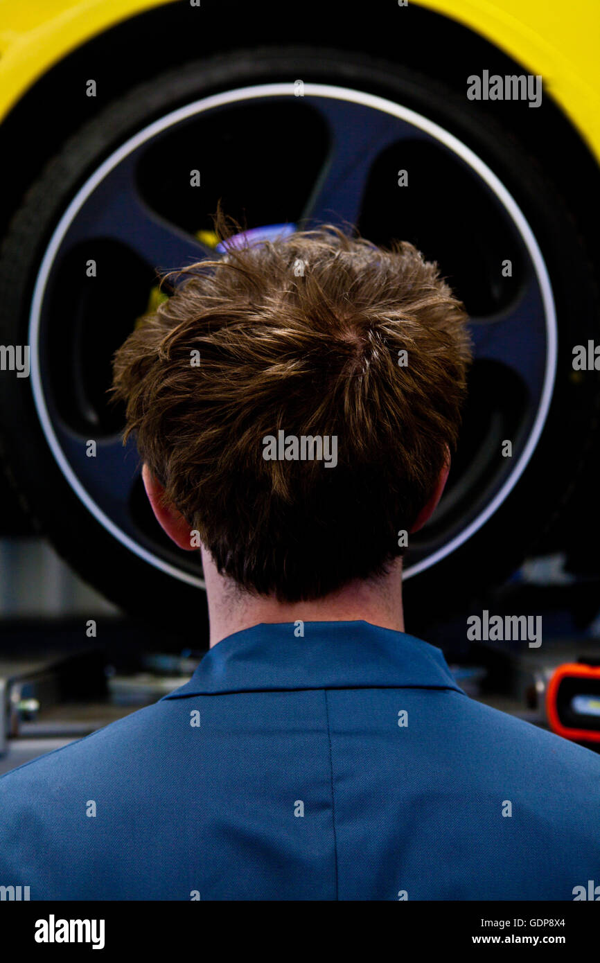 Male mechanic looking at sports car wheel rim, rear view Stock Photo ...