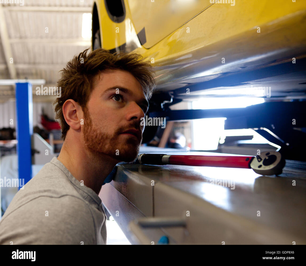 Male mechanic looking underneath sports car Stock Photo - Alamy