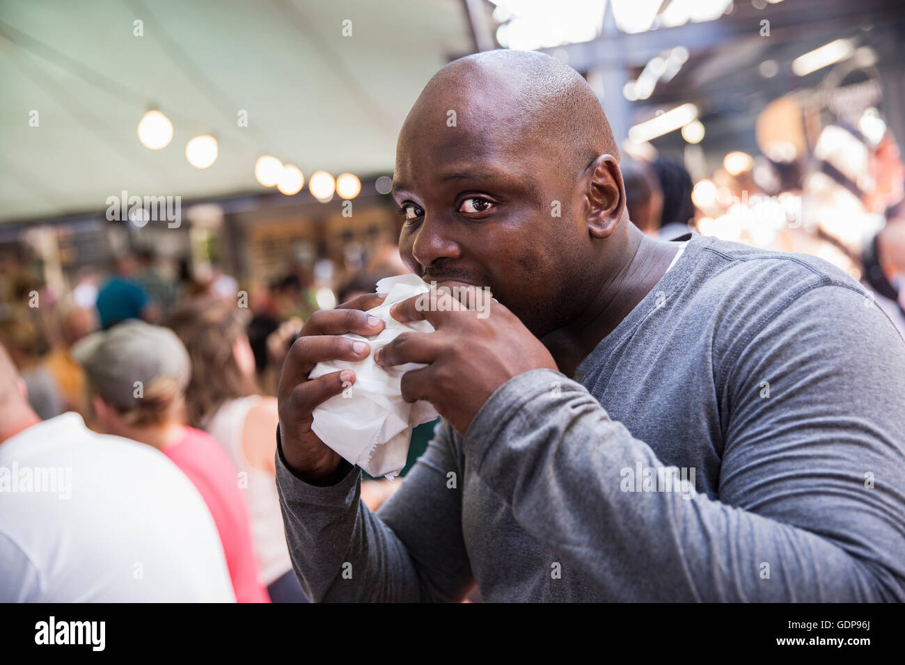 Male customer eating burger at cooperative food market stall Stock ...