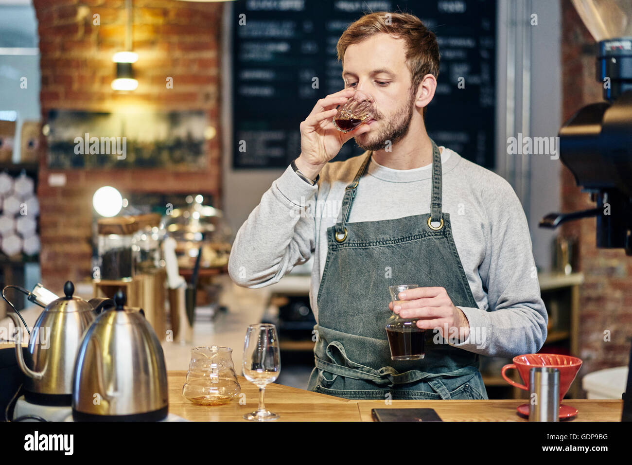 Male barista tasting coffee at coffee shop kitchen counter Stock Photo ...