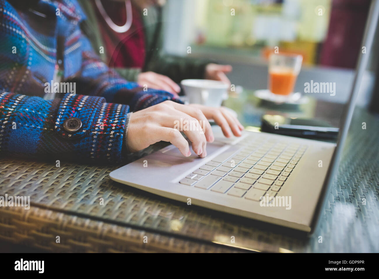 Two women in cafe using laptop, mid section Stock Photo - Alamy