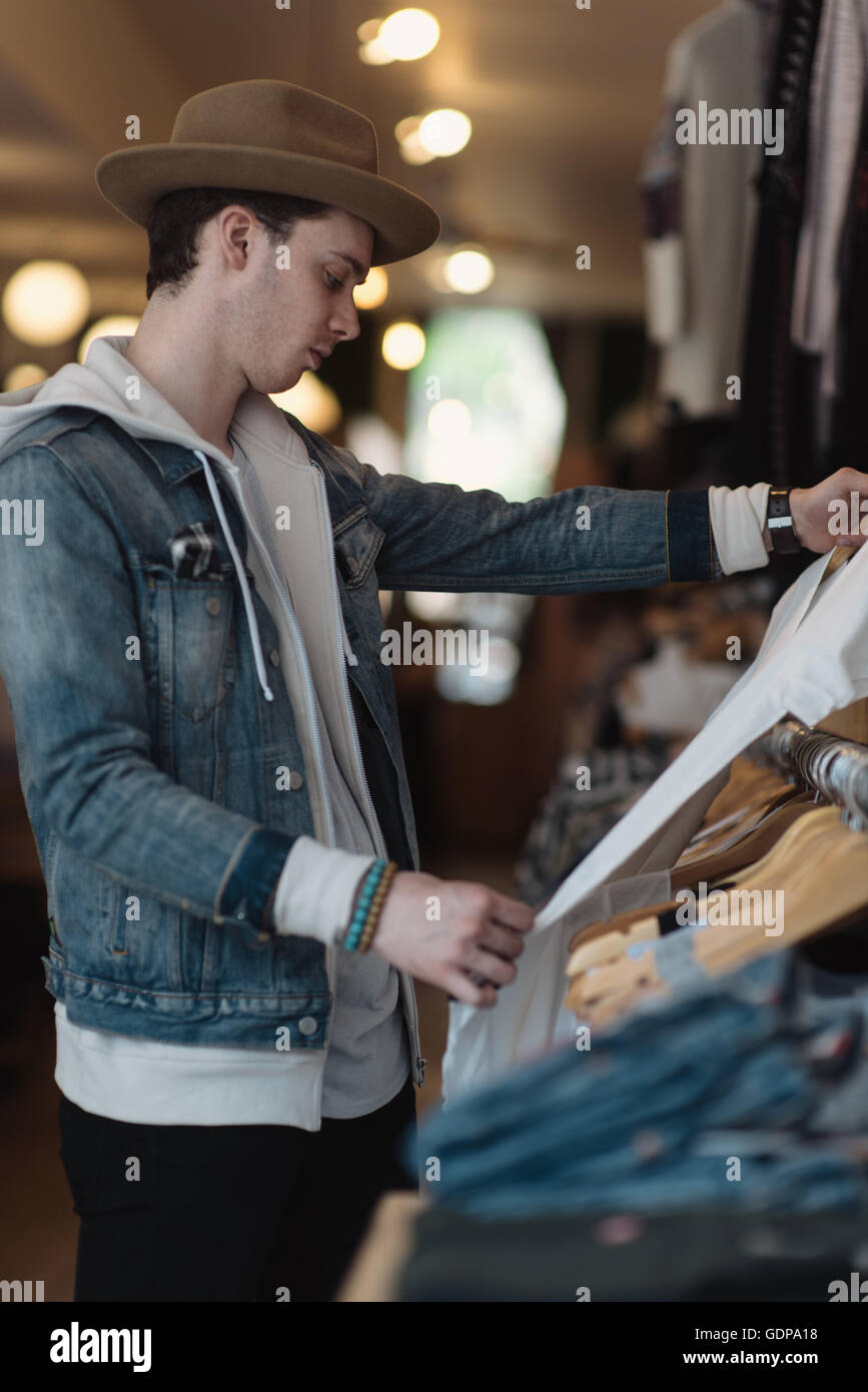 Young man looking at clothes in clothes shop Stock Photo - Alamy