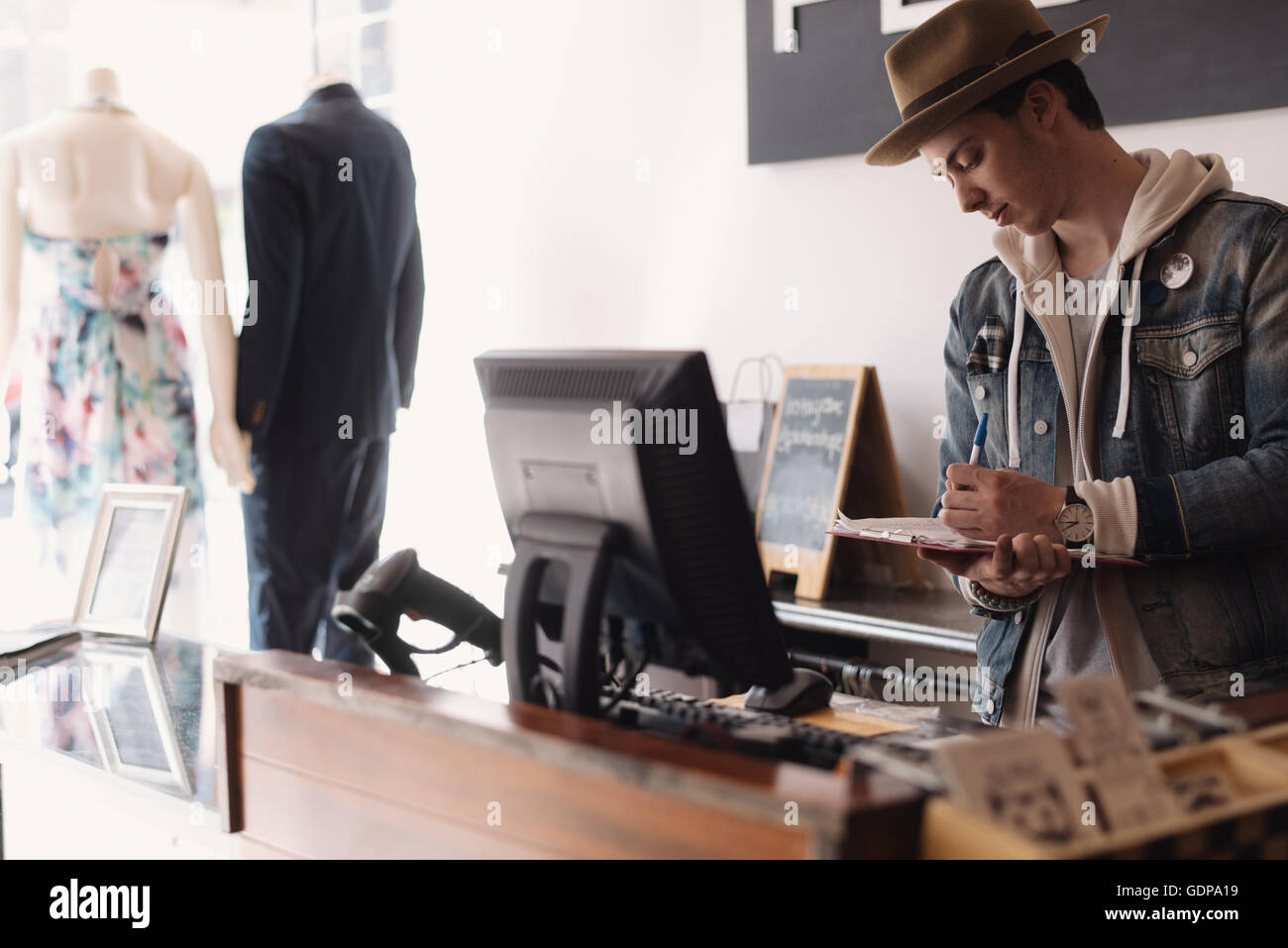 Young male shop worker standing behind counter, making notes Stock ...