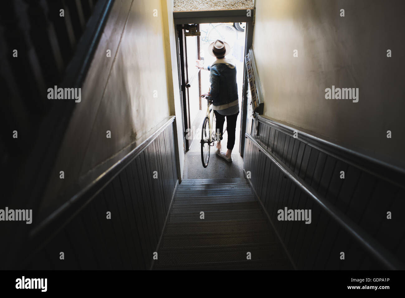 Young man at bottom of stairs, exiting building with bike, elevated ...