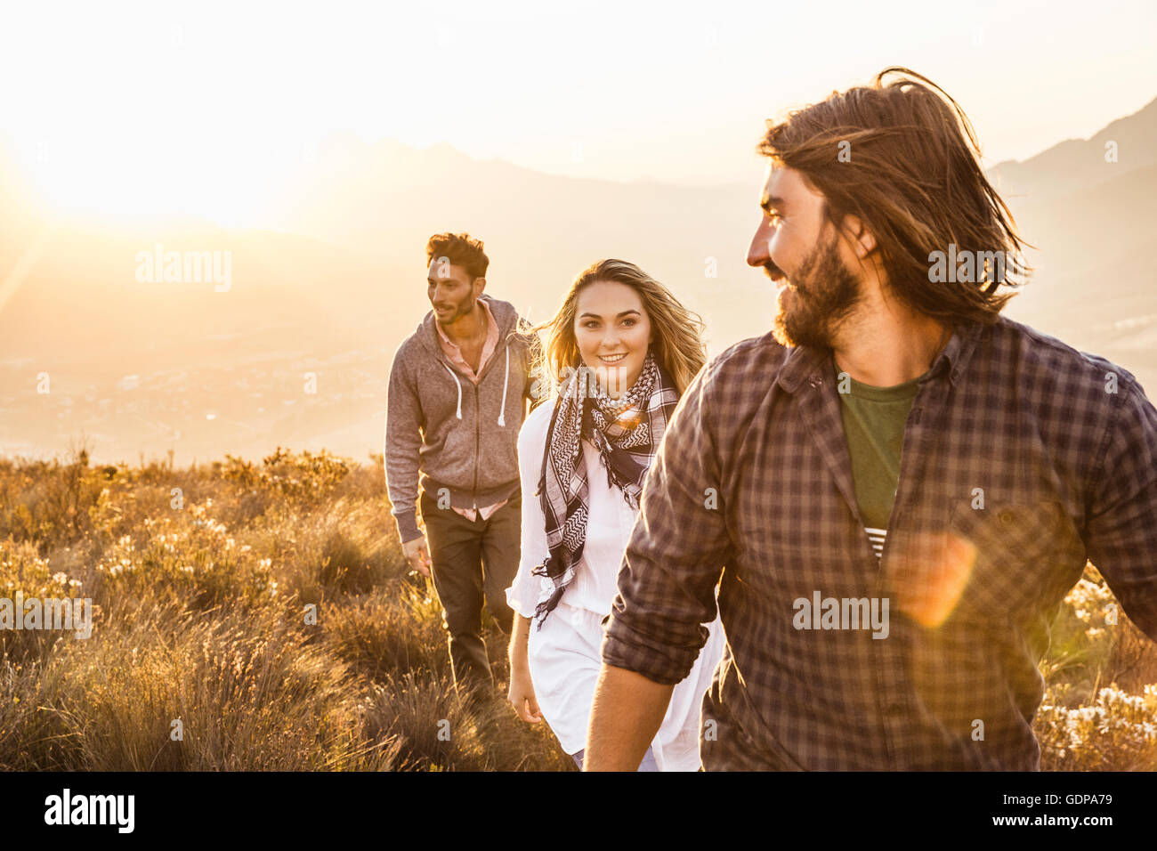 Friends rambling on grassland smiling Stock Photo - Alamy