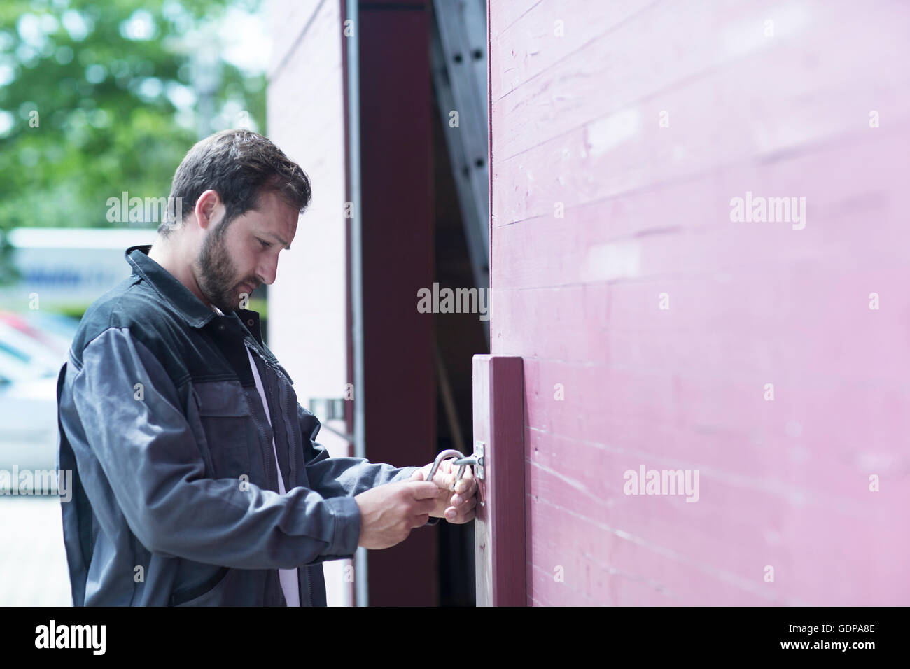 Man unlocking padlock on warehouse Stock Photo - Alamy
