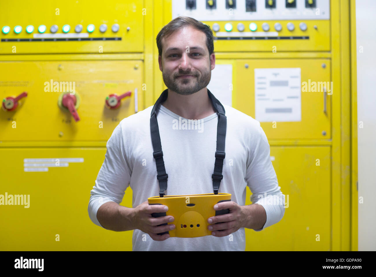 Man in front of yellow control panel smiling Stock Photo - Alamy