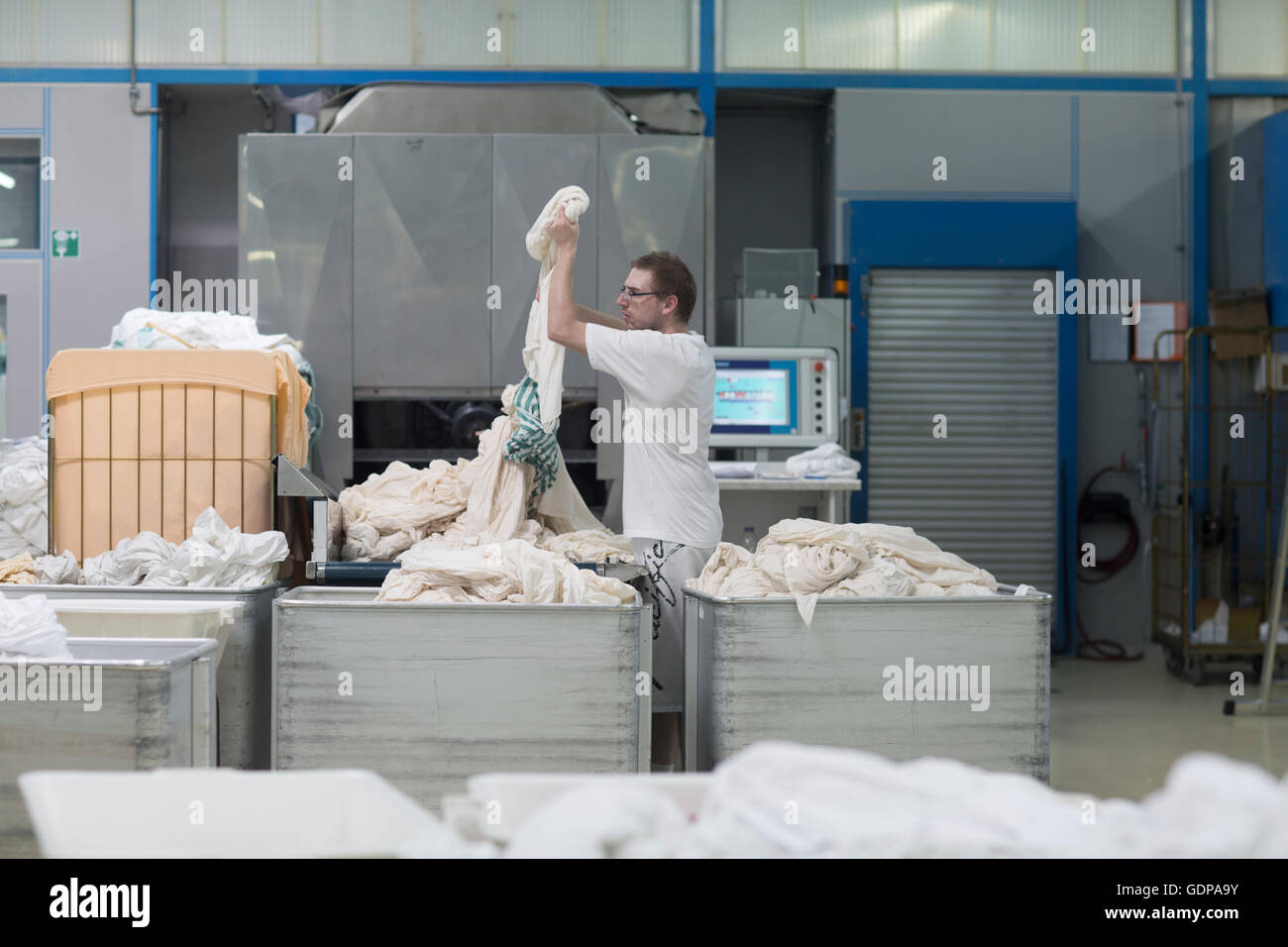 Man working in launderette sorting laundry Stock Photo - Alamy