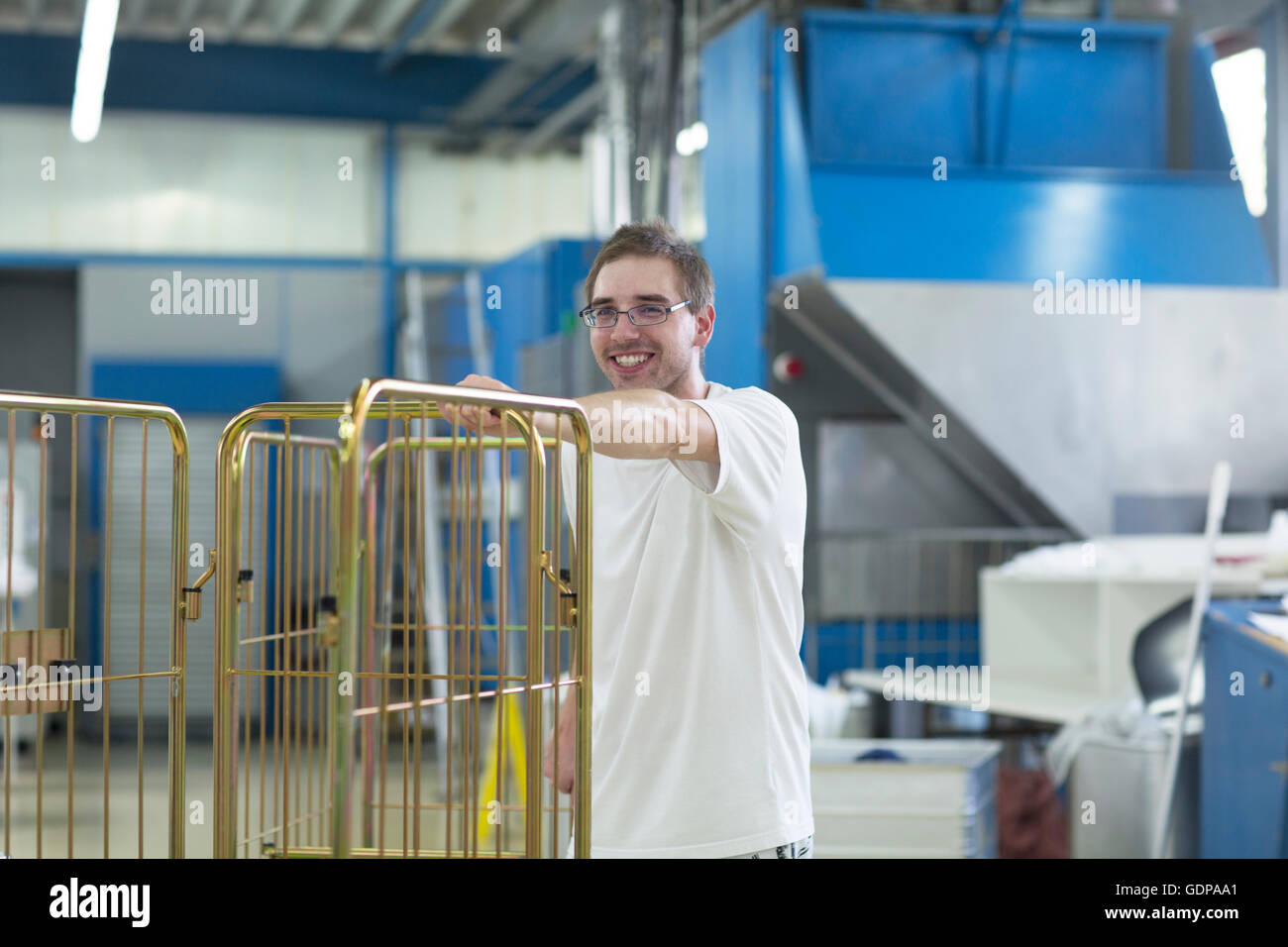 Man in launderette pushing roll cage Stock Photo - Alamy