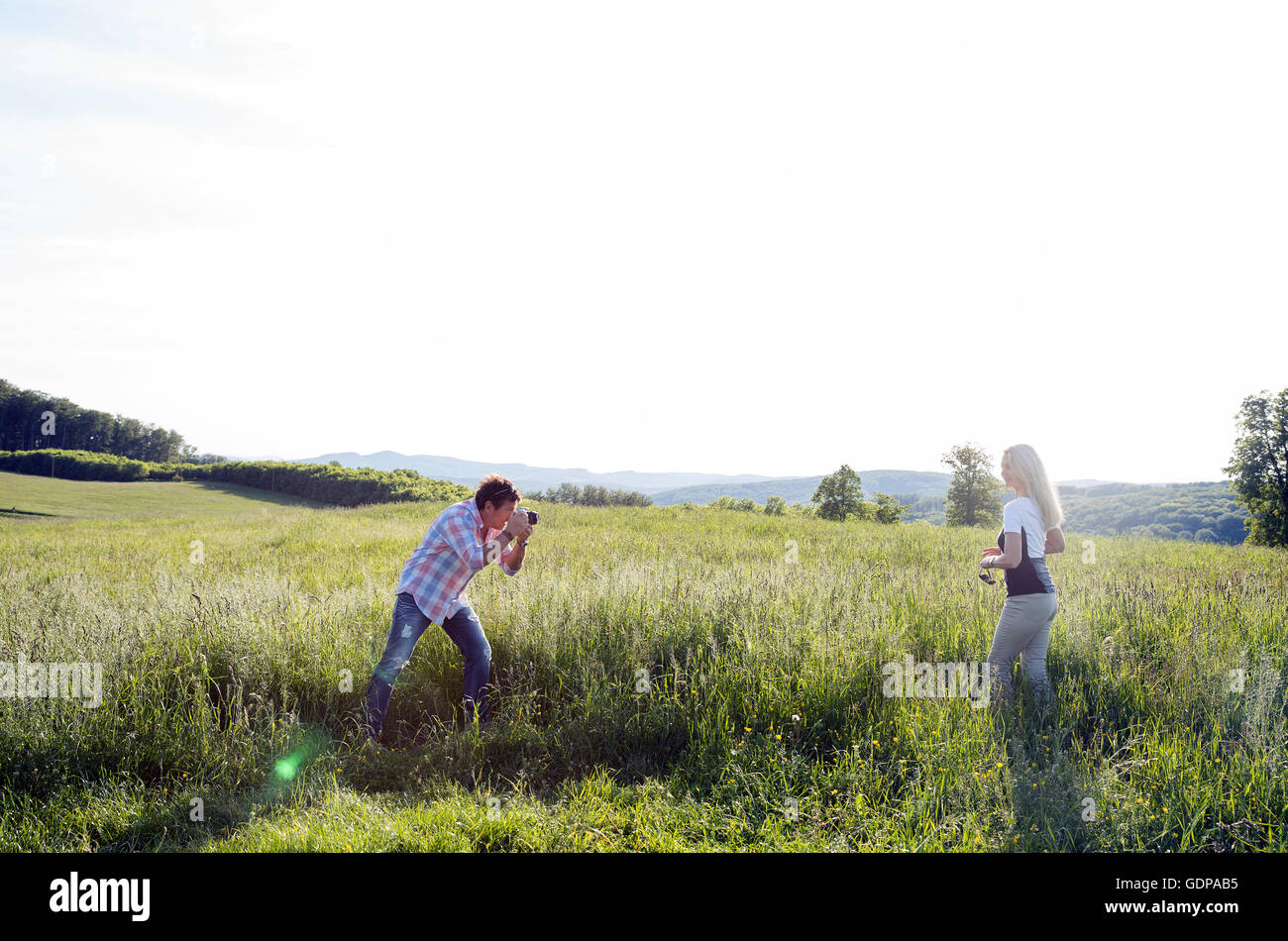 Man photographing woman in field Stock Photo - Alamy