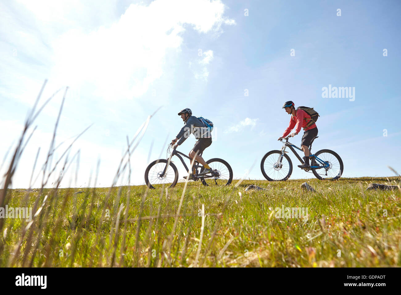 Side view of cyclists cycling on hillside Stock Photo - Alamy