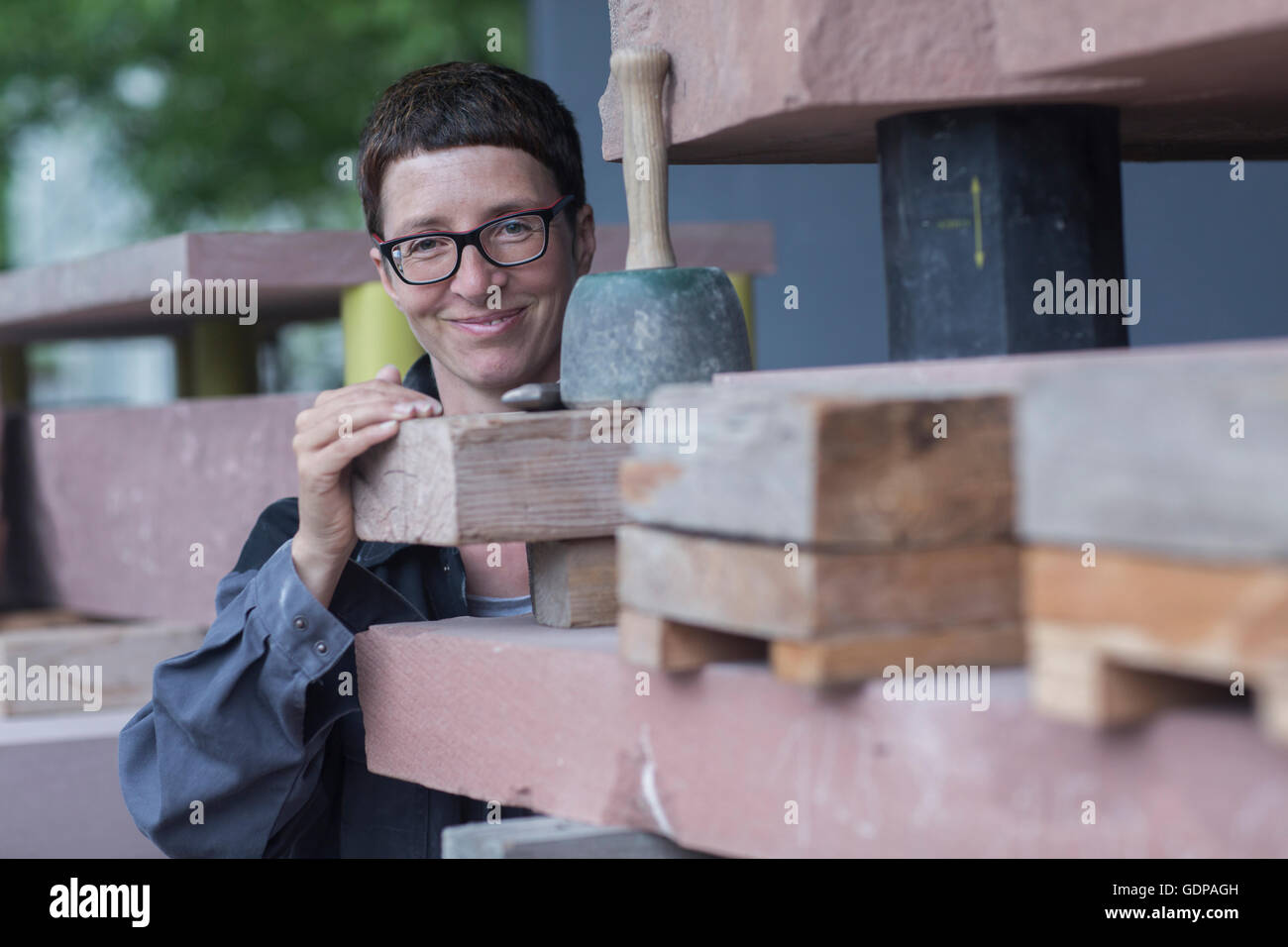 Stonemason quality checking blocks of stone, looking at camera smiling ...