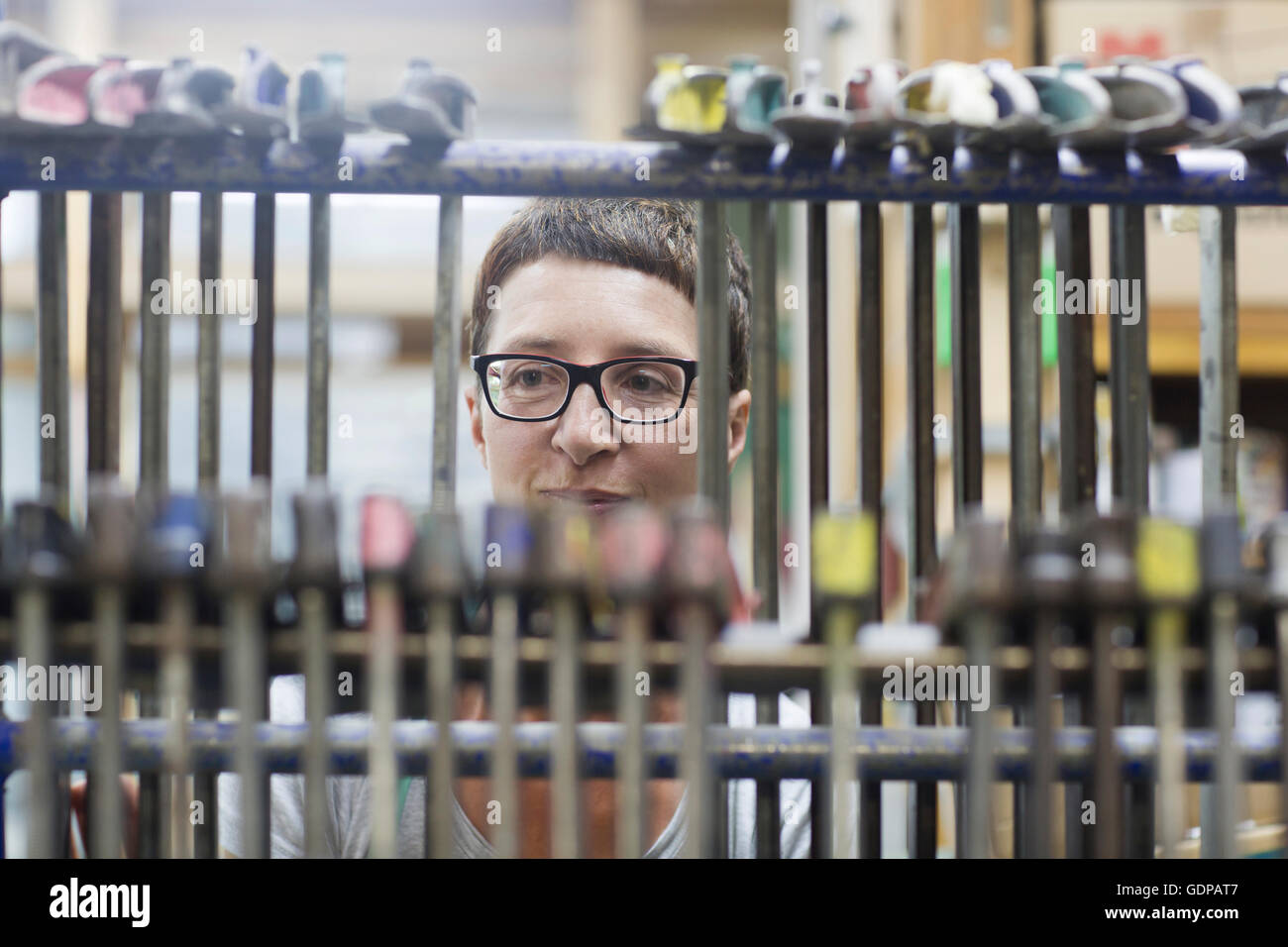View through hanging clamp tools of woman in workshop Stock Photo - Alamy