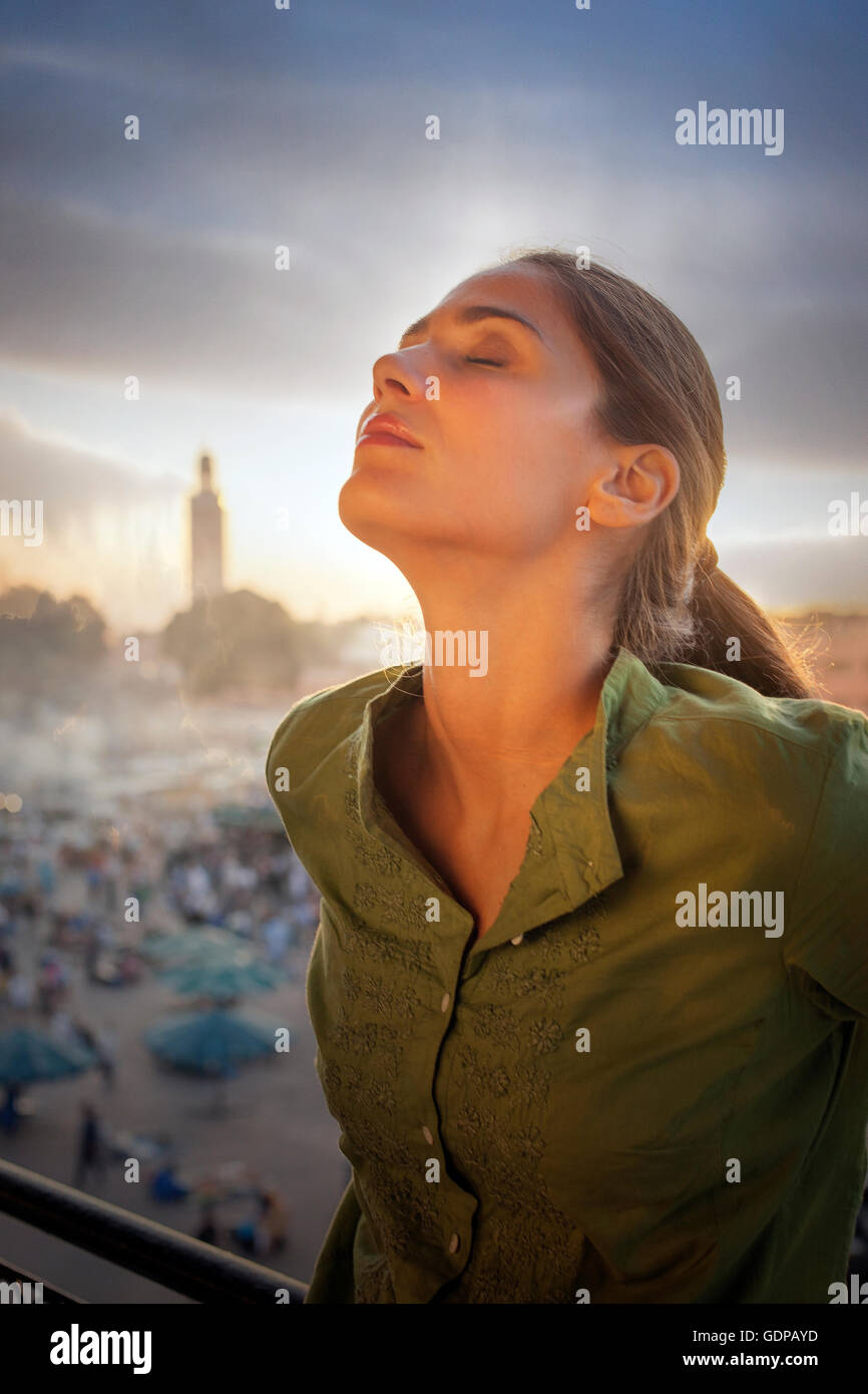 Woman in front of Jemaa el-Fnaa Square, head back, eyes closed ...