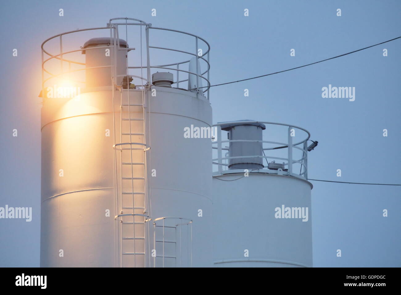 Illuminated white industrial silos in twilight Stock Photo - Alamy