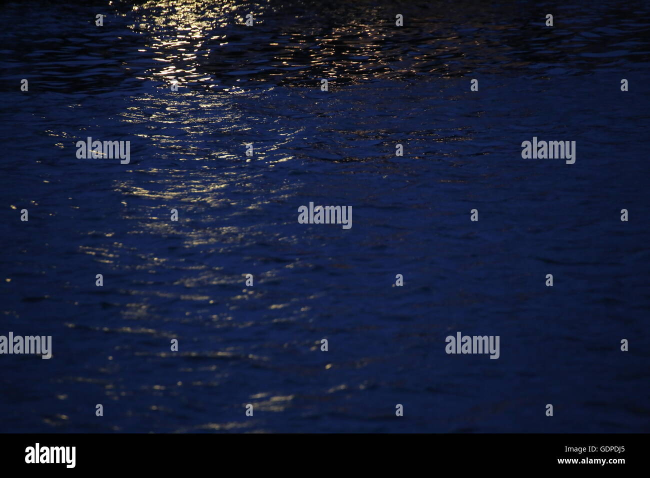 Reflections of yellow light on water in the night. Two different wave ...