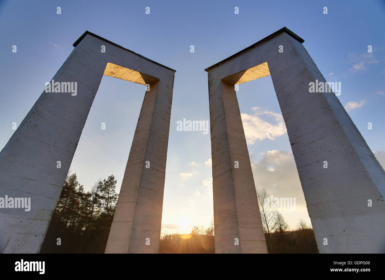 Symmetrical wide angle view of two concrete arches in front of the sun ...