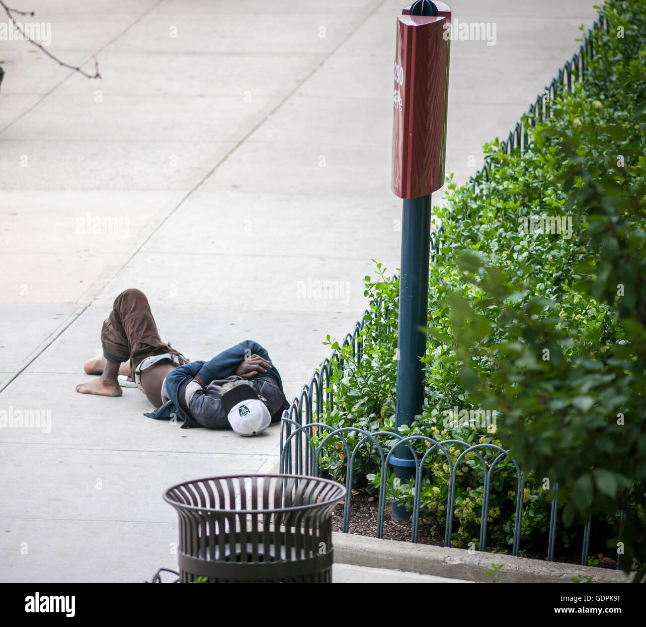 A homeless individual sleeps on the sidewalk in the Chelsea ...
