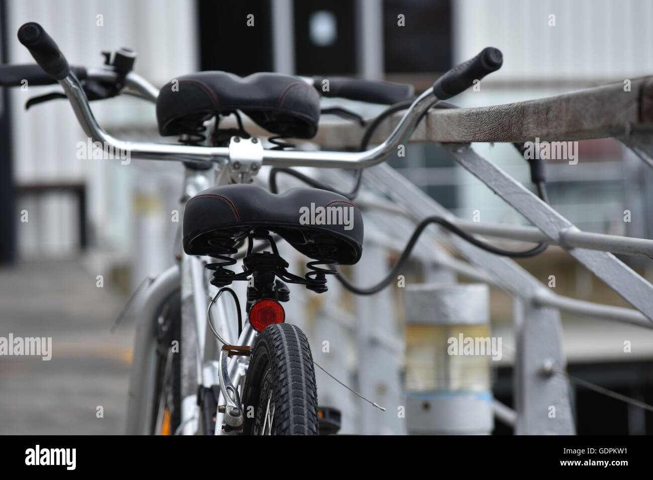 Tandem bicycle chained to metal railing with chain lock Stock Photo - Alamy