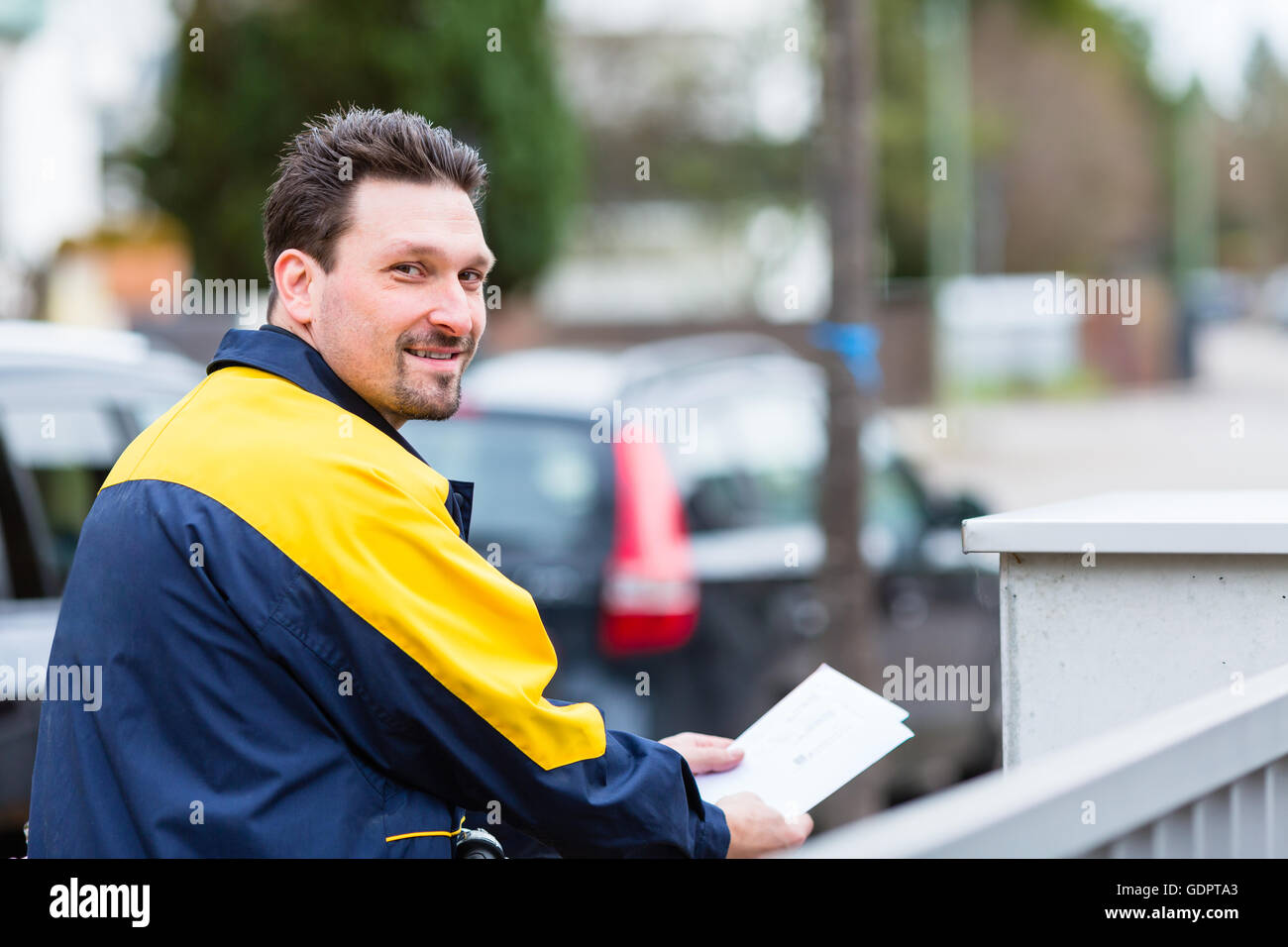Postman delivering letters to mailbox of recipient Stock Photo - Alamy