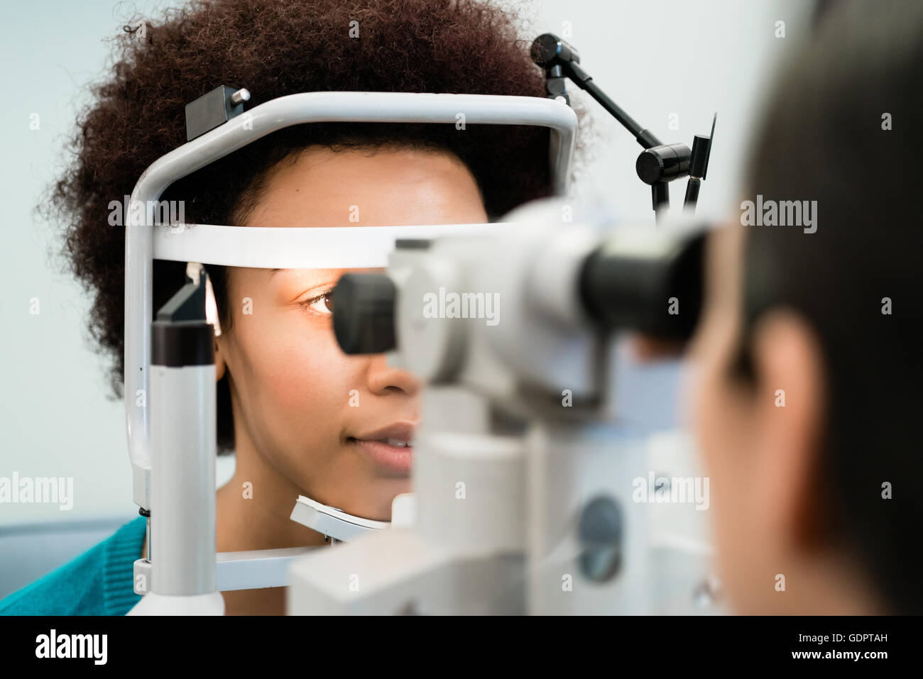 Woman having eyes measured with refractometer at optician or ...