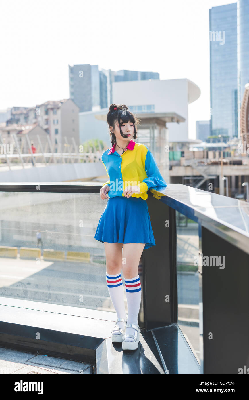 Young beautiful stylish asian millennial woman outdoot in the city, leaning on handrail ...