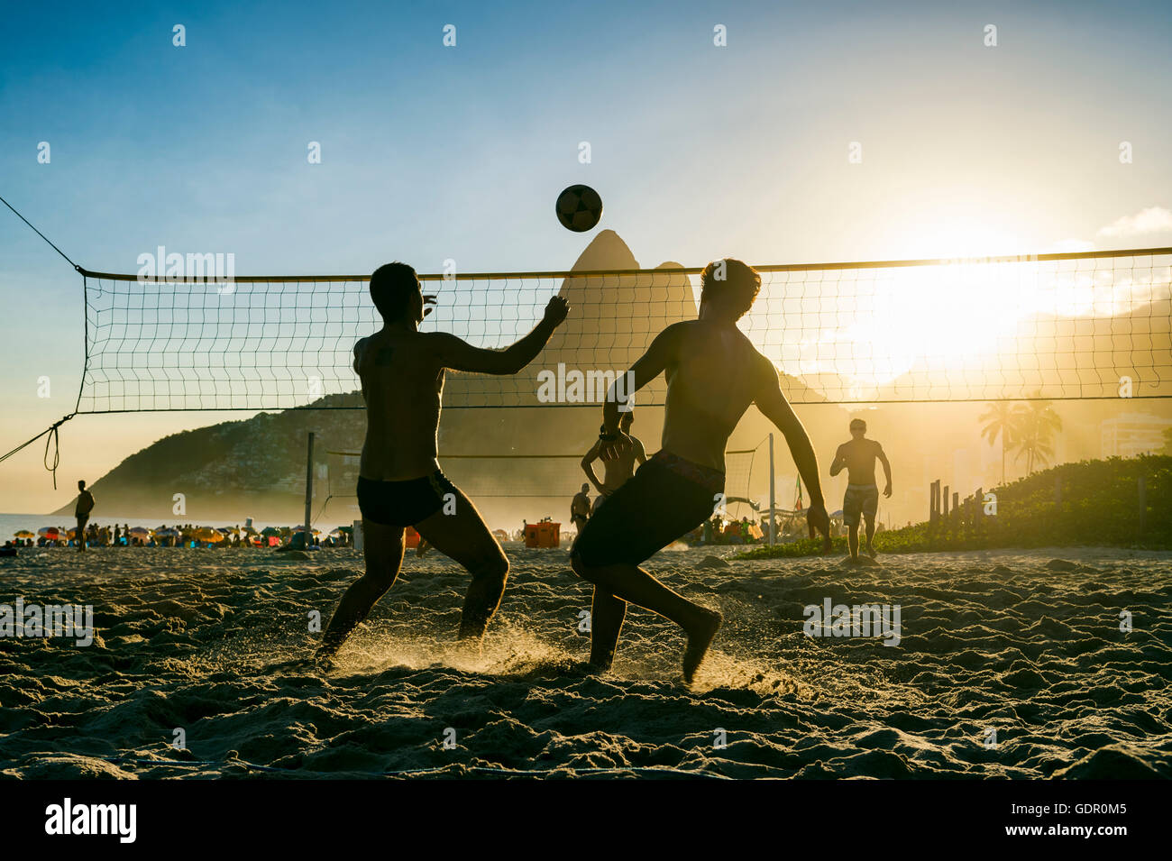 Silhouettes of Brazilians playing futevolei (footvolley) against a ...