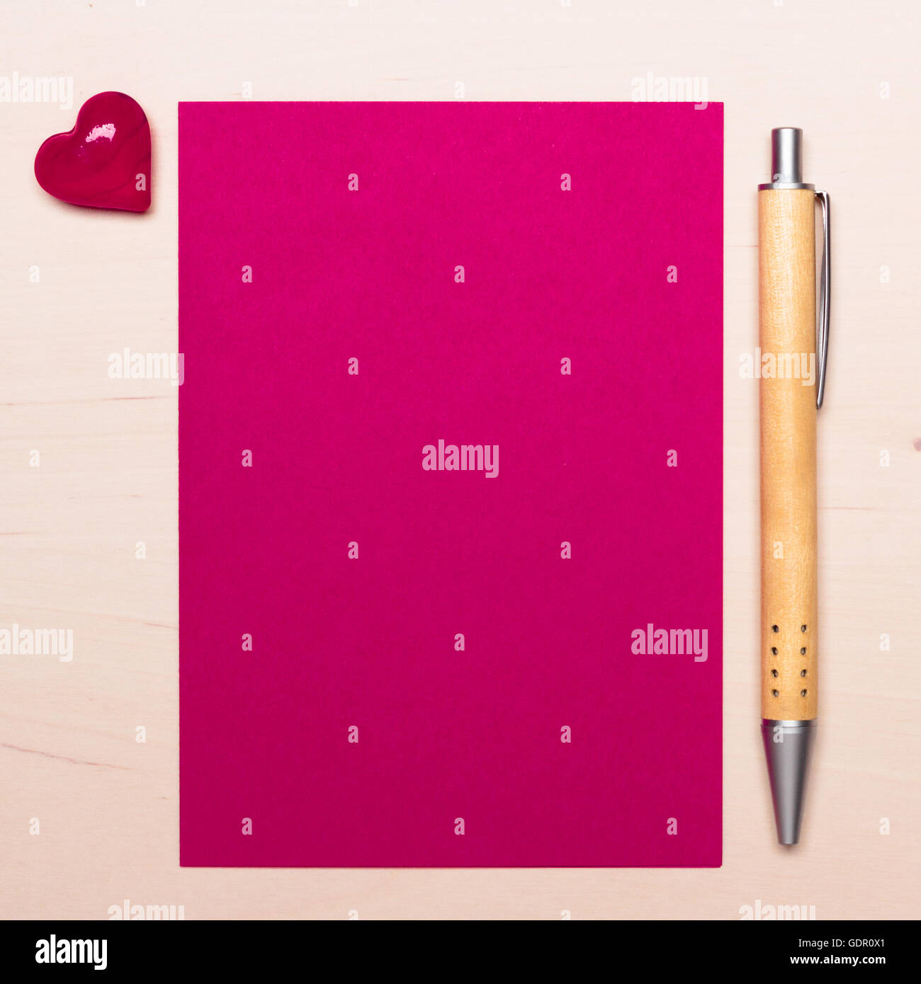 Pink blank sheet of paper with heart love symbol and pen on wooden ...