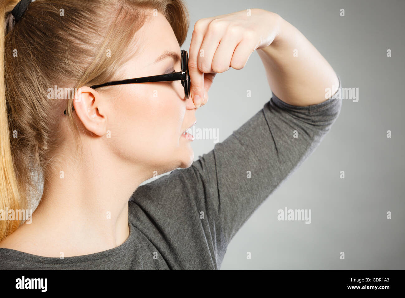 Bad smell concept. Young woman feels disgust pinches her nose with ...