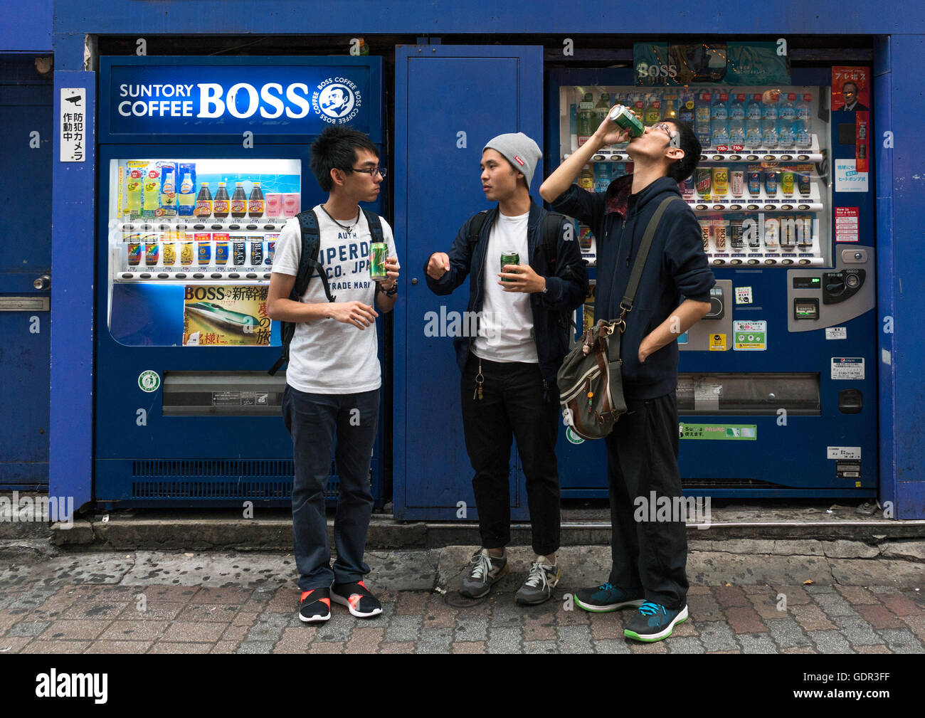 Young men using a drinks vending machine, Kanto region, Tokyo, Japan ...