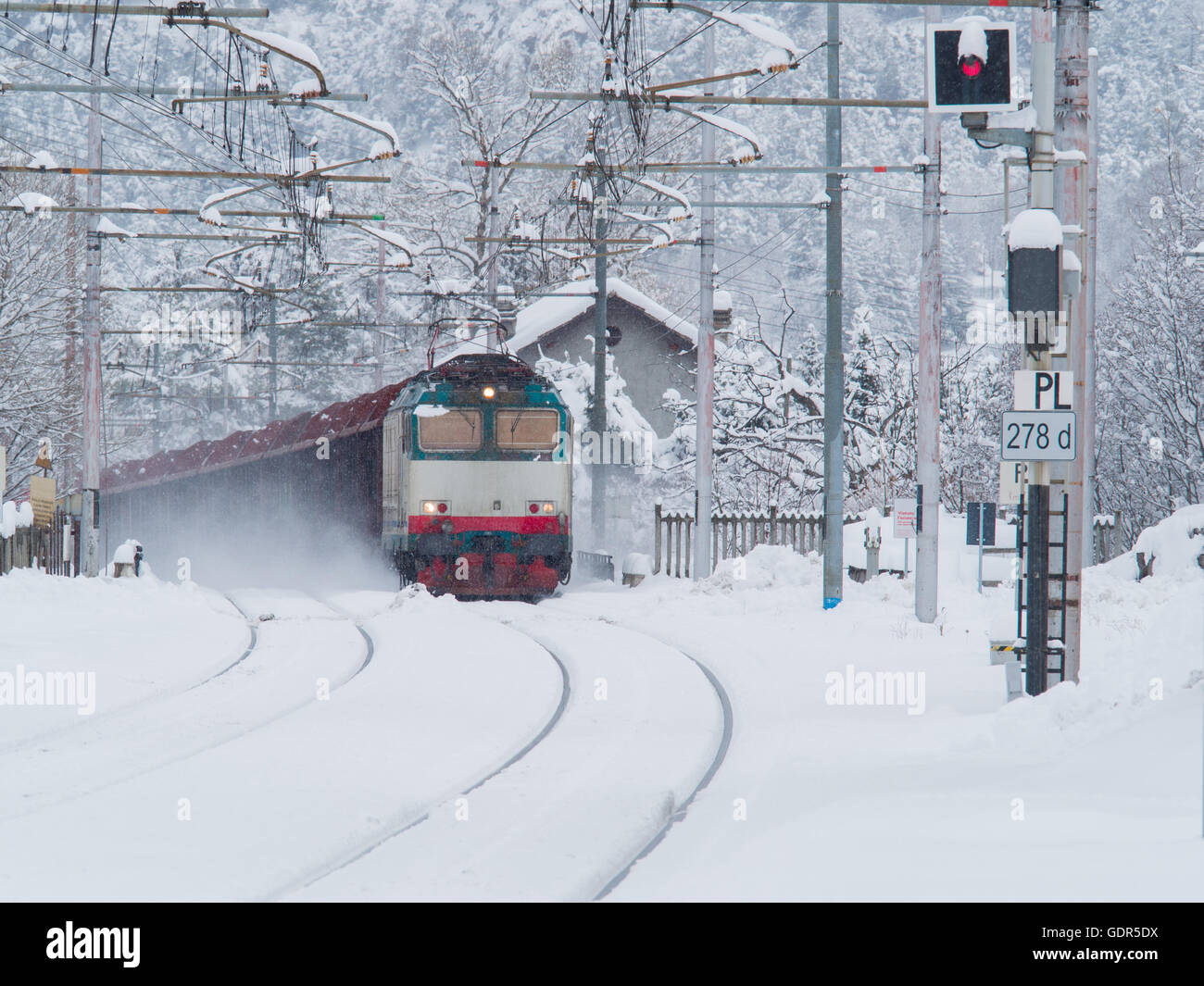 Freight train running on the railway tracks in winter while is snowing ...