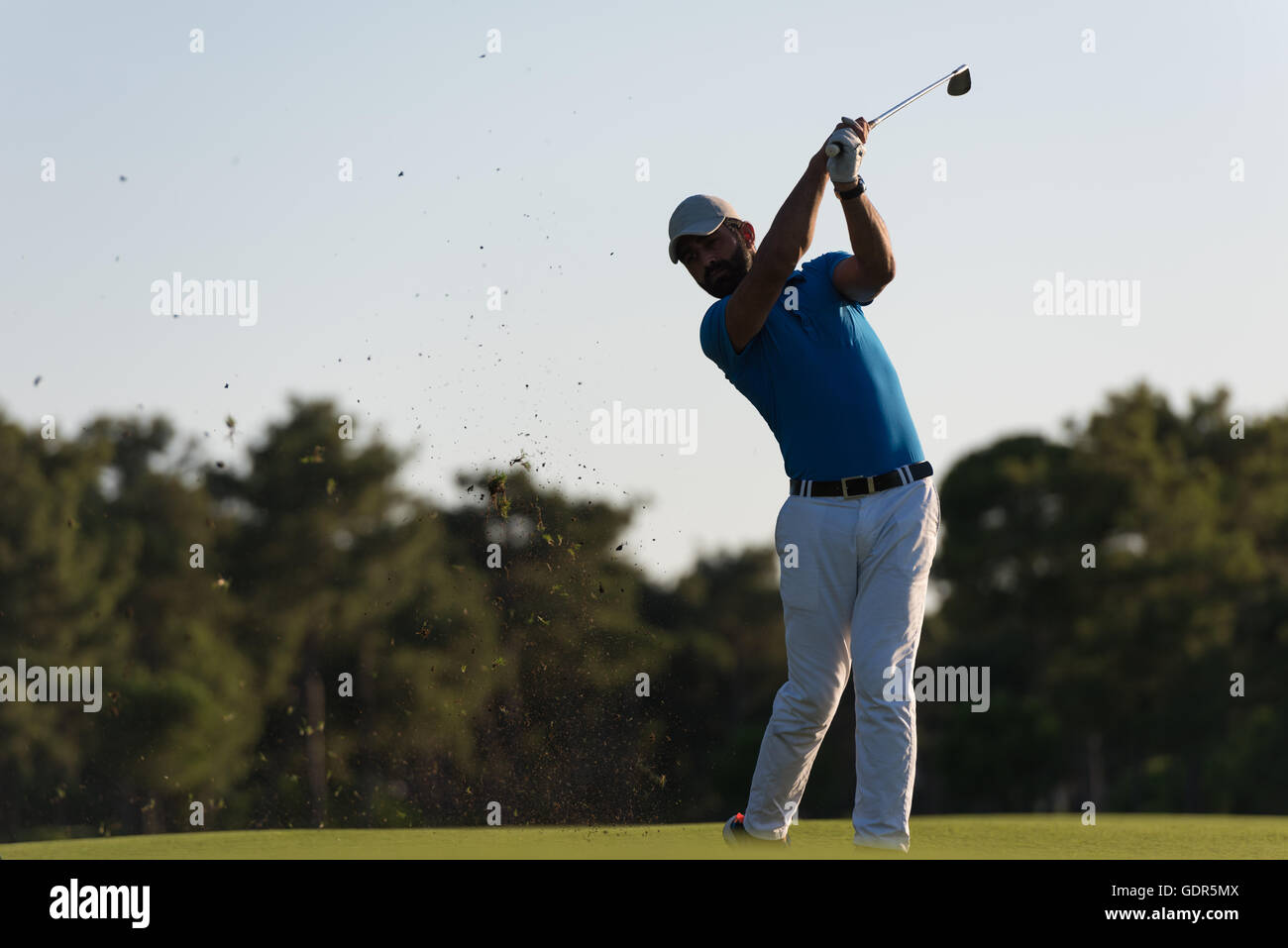 golfer hitting long shot with driver on course at beautiful sunset ...