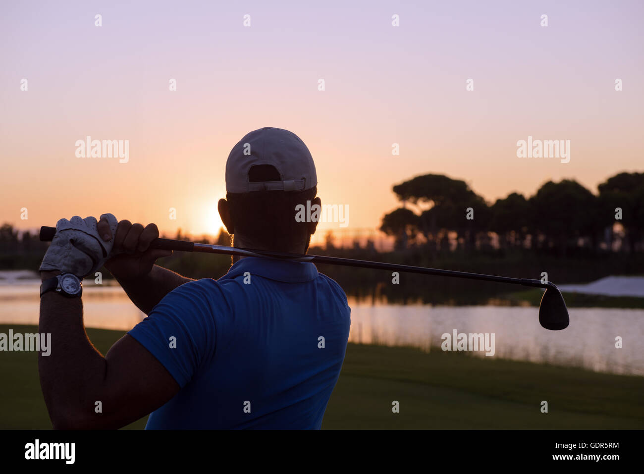 golfer hitting long shot with driver on course at beautiful sunset ...