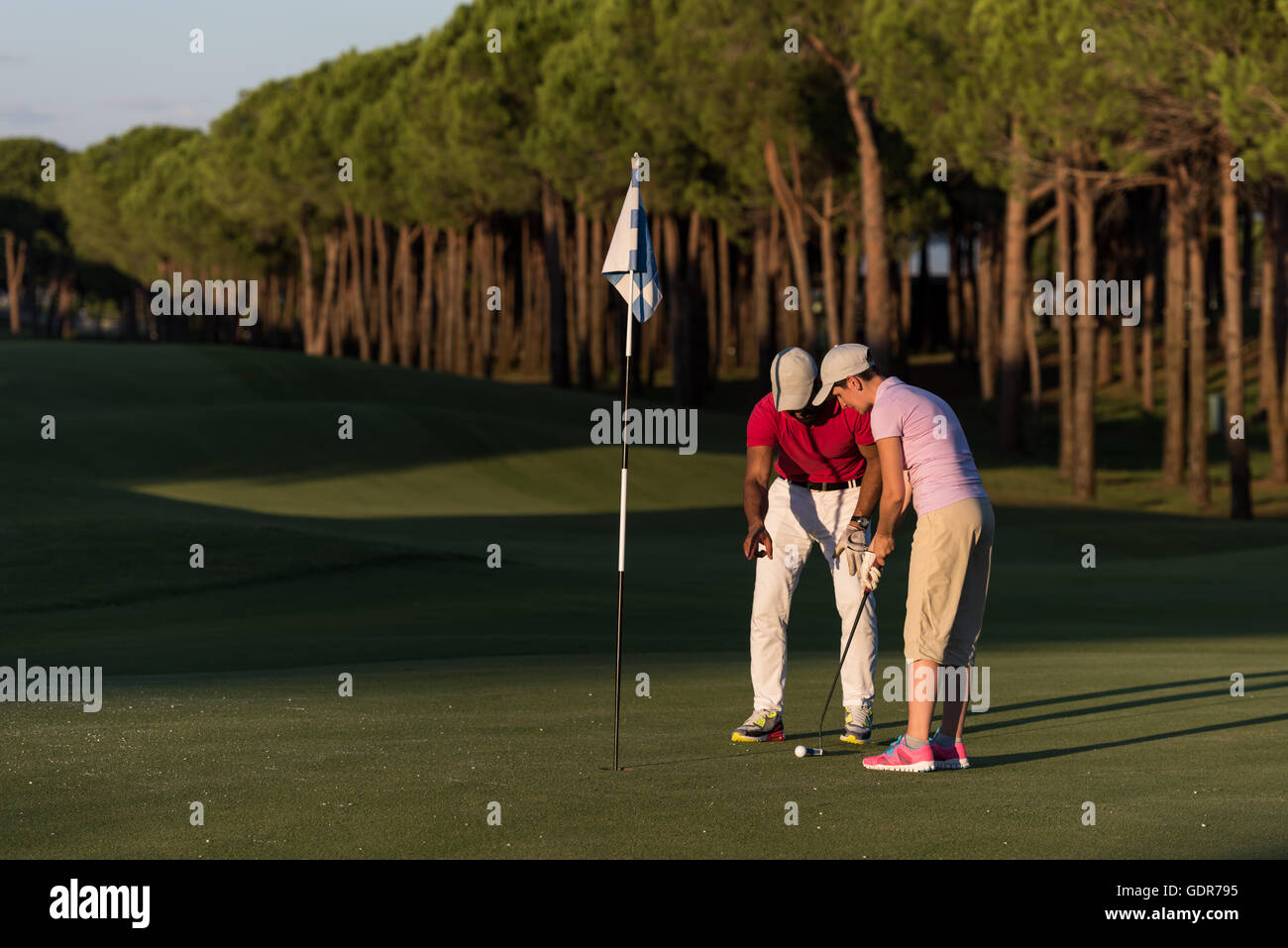 male golf instructor teaching female golf player, personal trainer ...