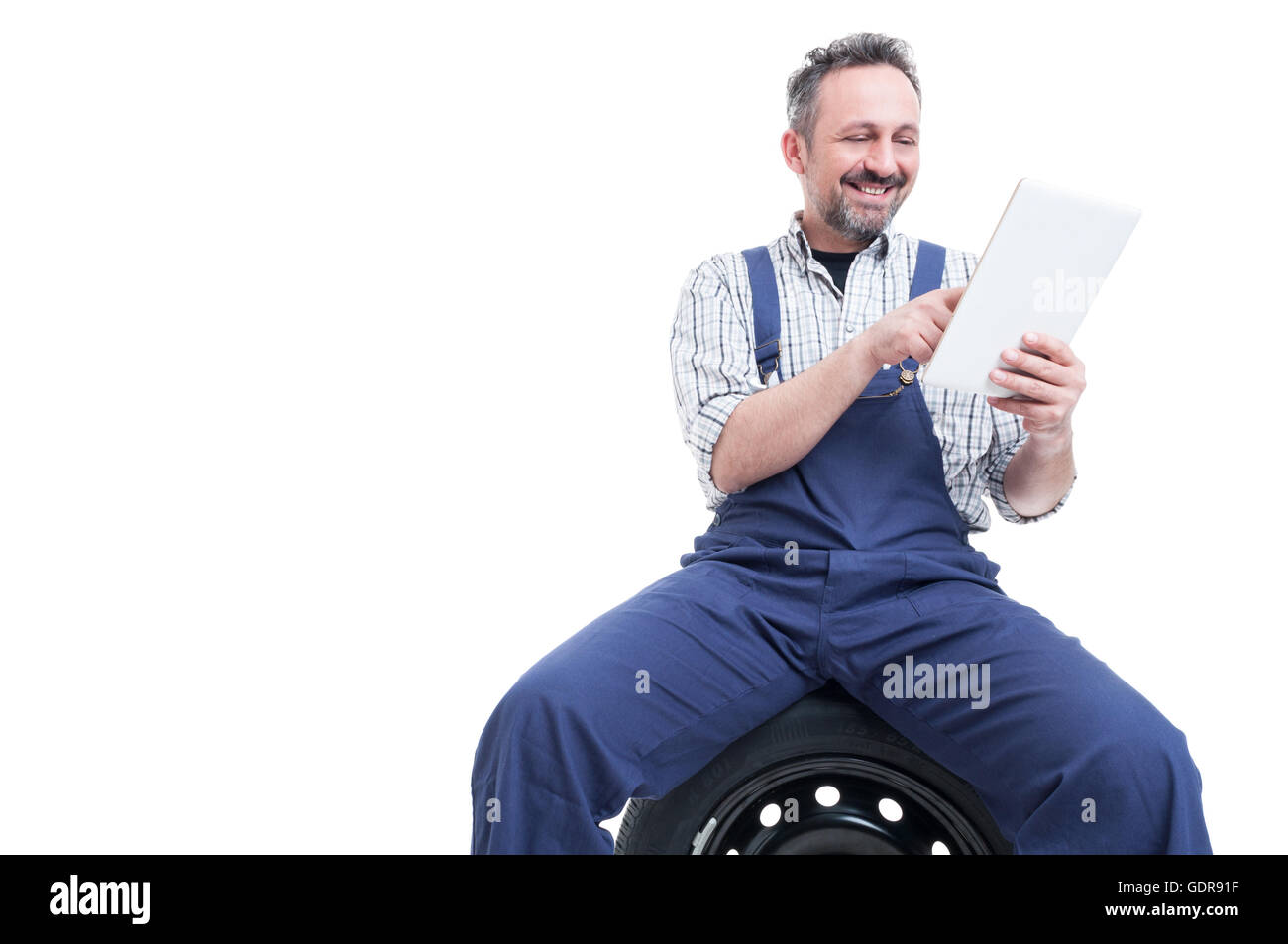 Happy attractive mechanic reading something on modern tablet isolated ...