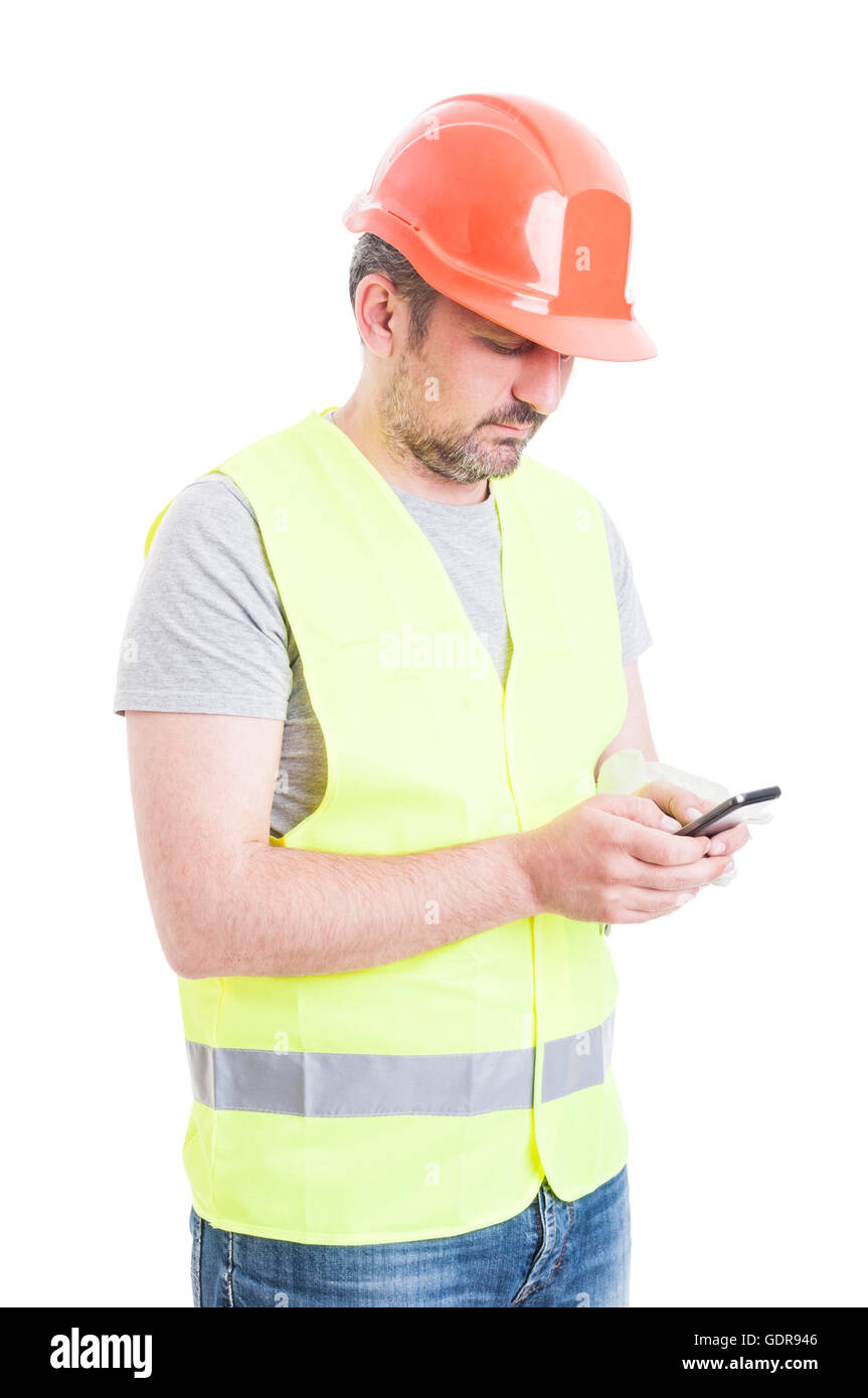 Busy male contractor wearing safety uniform and typing message or sms ...