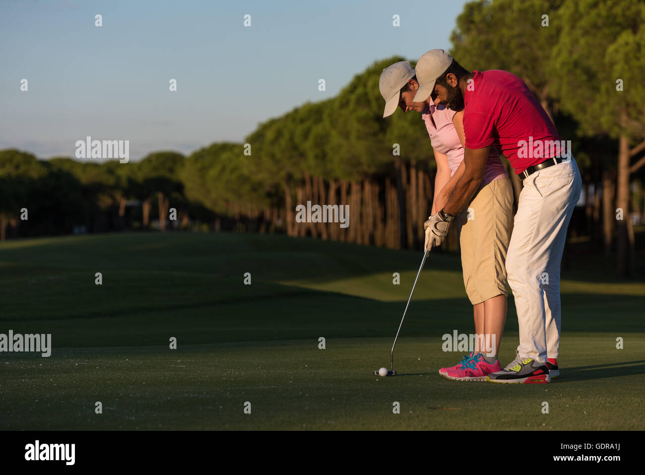 male golf instructor teaching female golf player, personal trainer ...