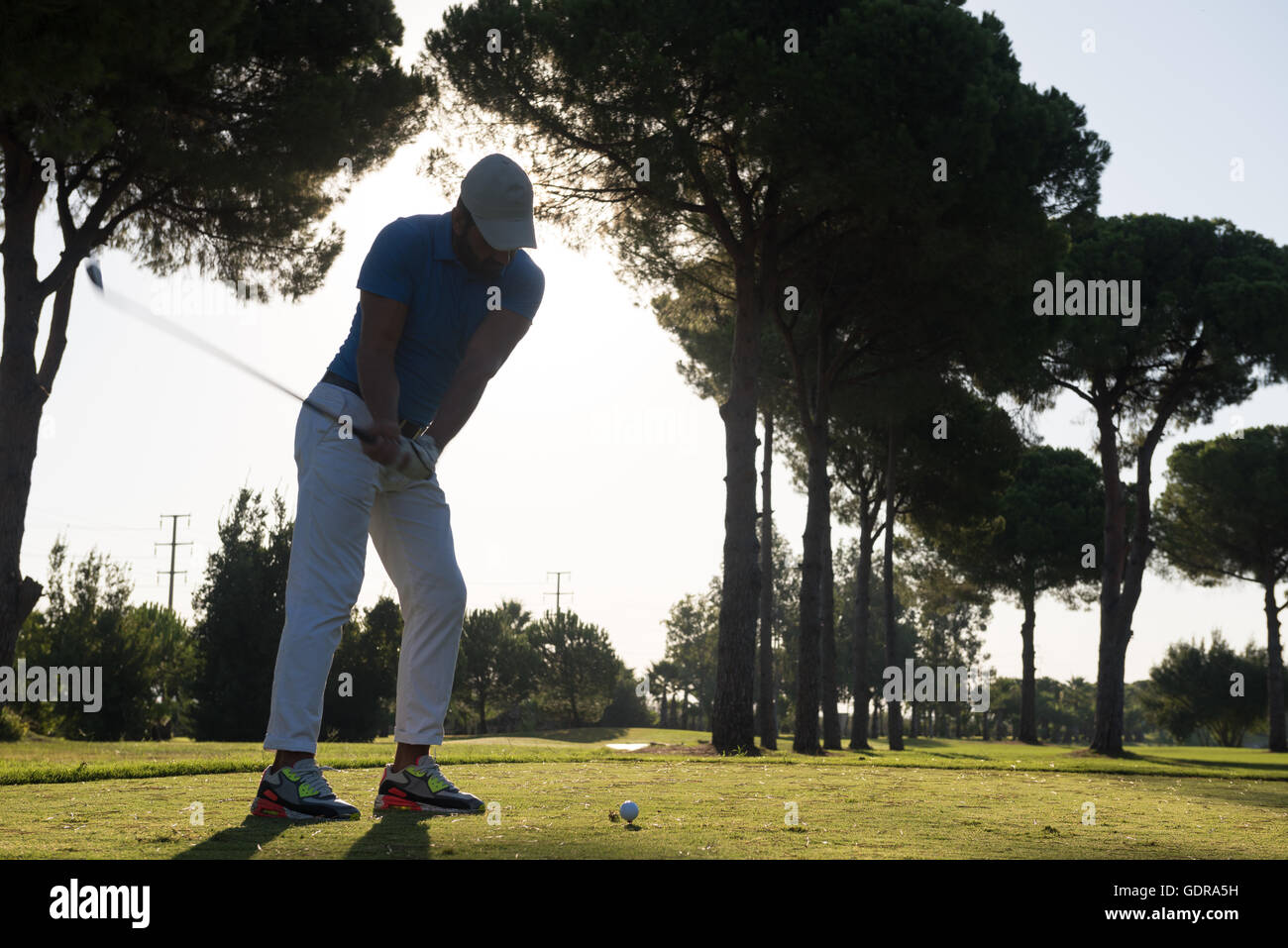 golf player hitting shot with club on course at beautiful morning with ...