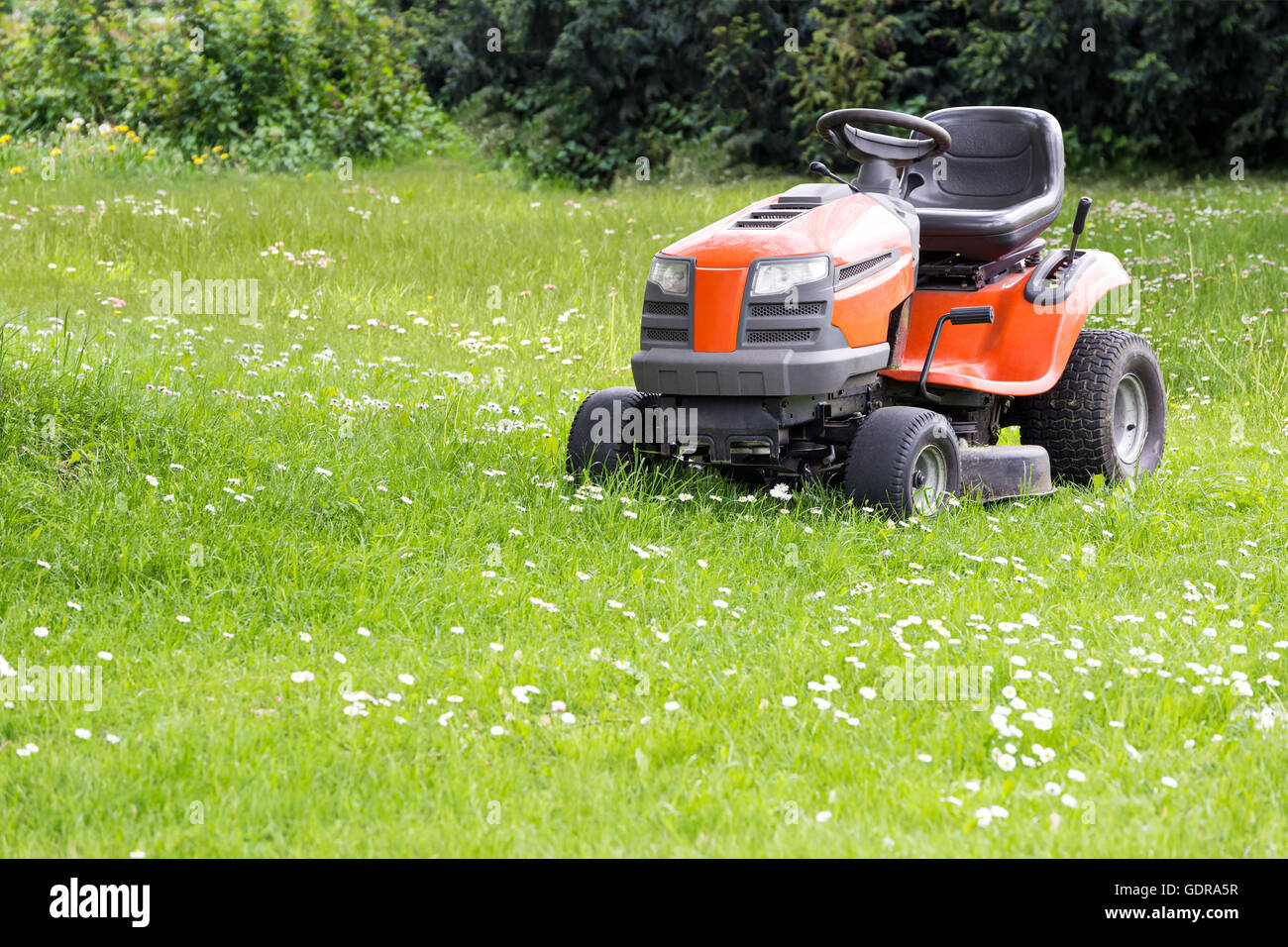 Lawn mower standing in spring garden Stock Photo - Alamy